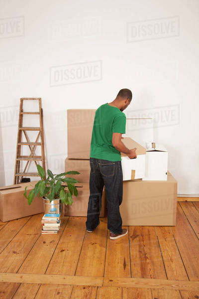 A man lifting a moving box to put it on top of other boxes - Stock ...