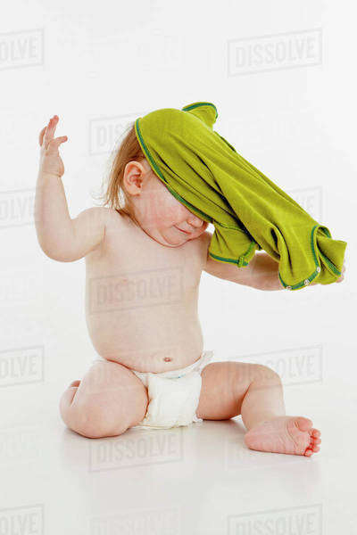 A baby girl pulling her shirt off - Royalty-free Stock Photo | Dissolve