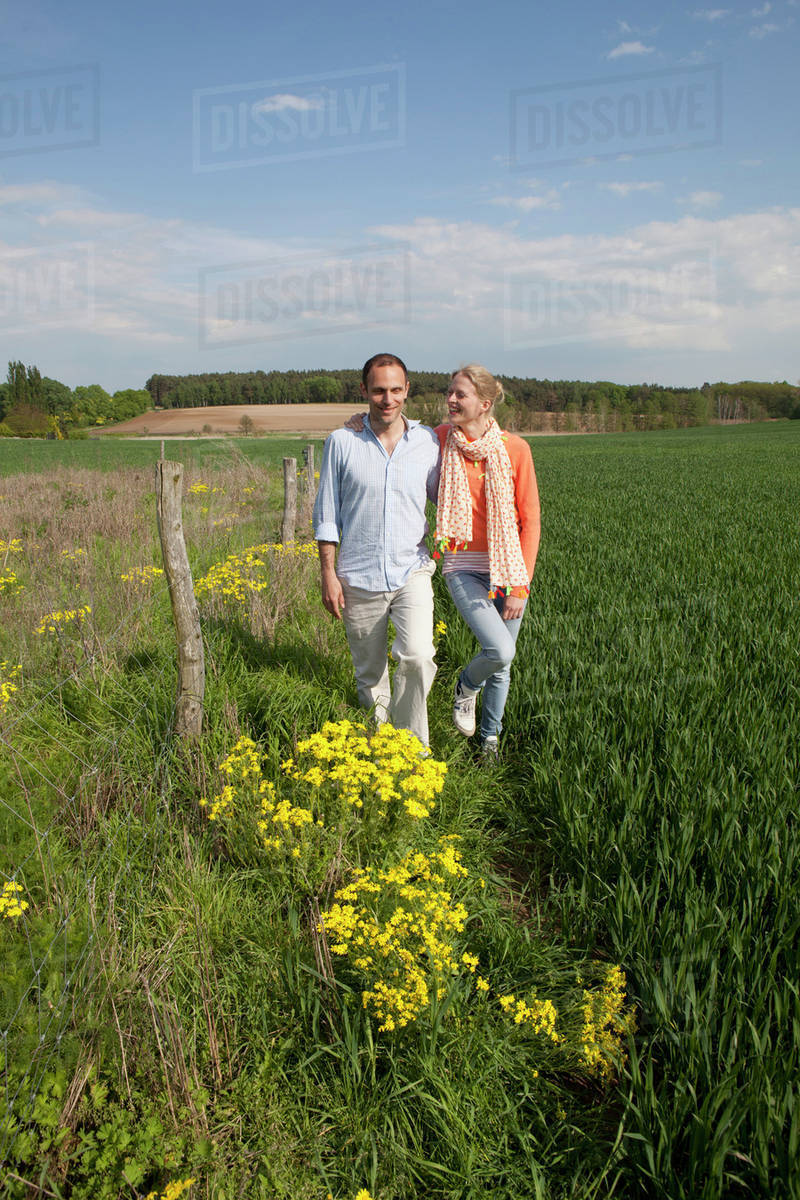 A couple walking side by side in a field - Stock Photo - Dissolve