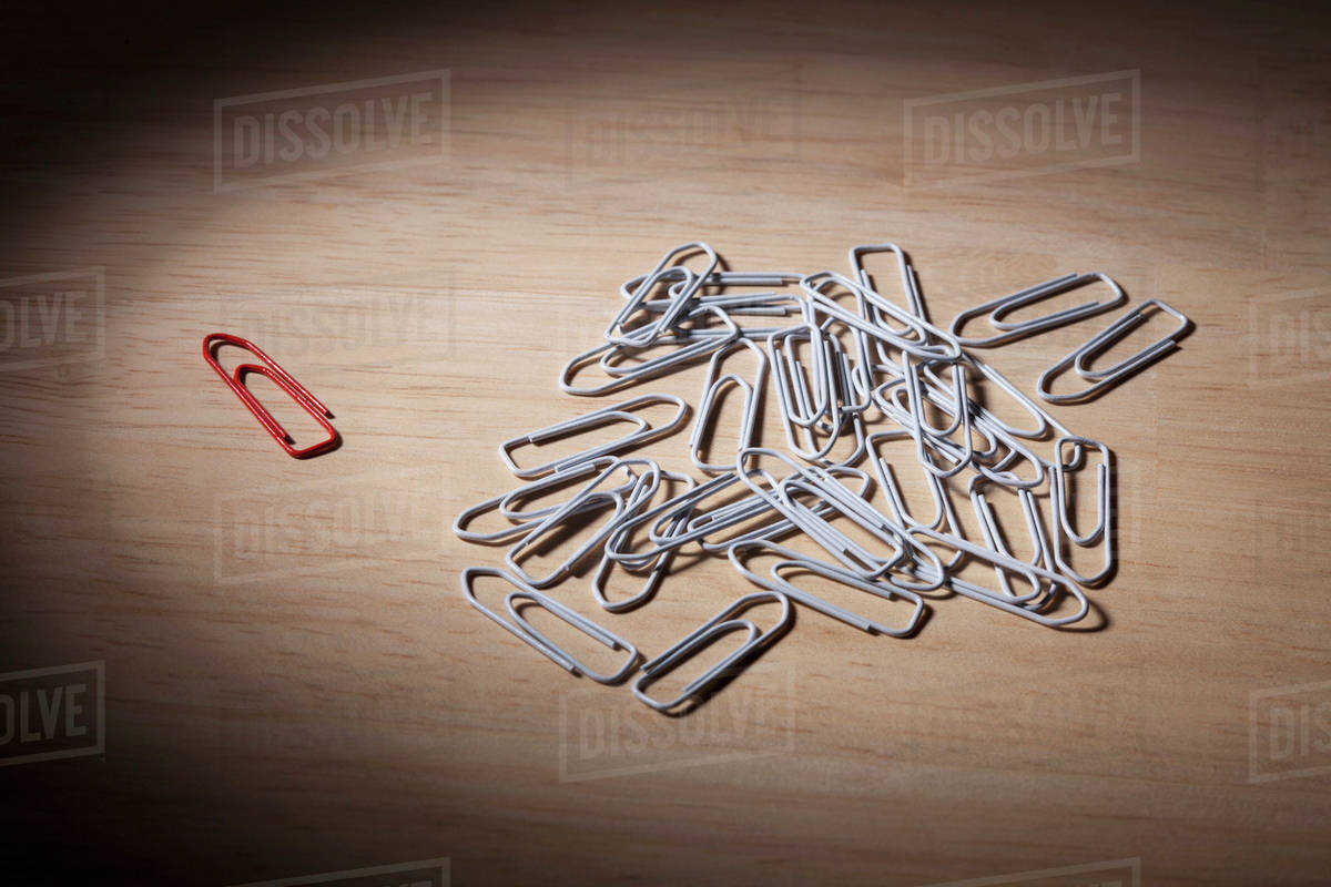 One red paperclip set apart from a heap of white paperclips - Royalty ...