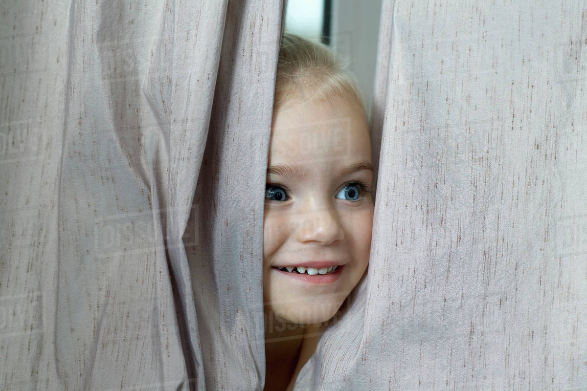 A young girl hiding between window curtains - Royalty-free Stock Photo ...