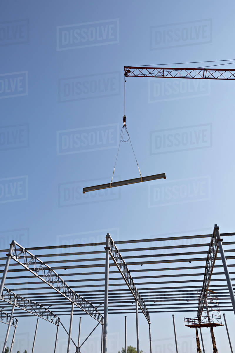 Crane lowering steel beam towards construction frame - Stock Photo ...