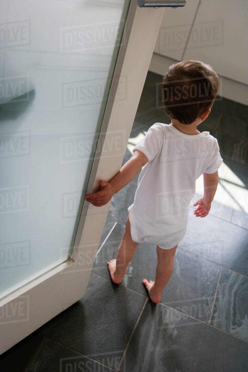 A little boy standing just inside a doorway - Stock Photo - Dissolve