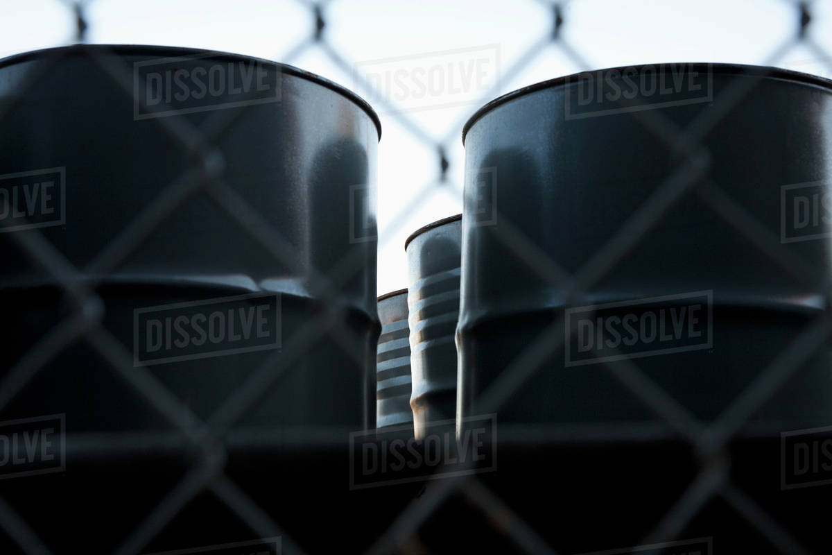 Black barrels behind wire mesh fence - Royalty-free Stock Photo | Dissolve