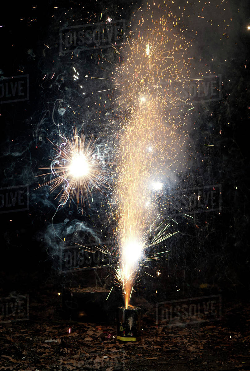 Sparks and smoke coming out of a firework exploding on a sidewalk ...