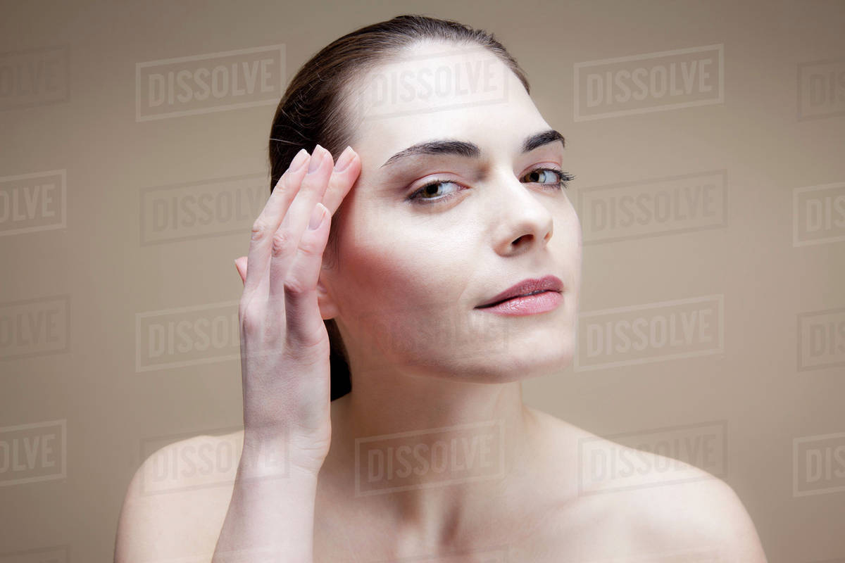 A young woman touching her temple - Stock Photo - Dissolve