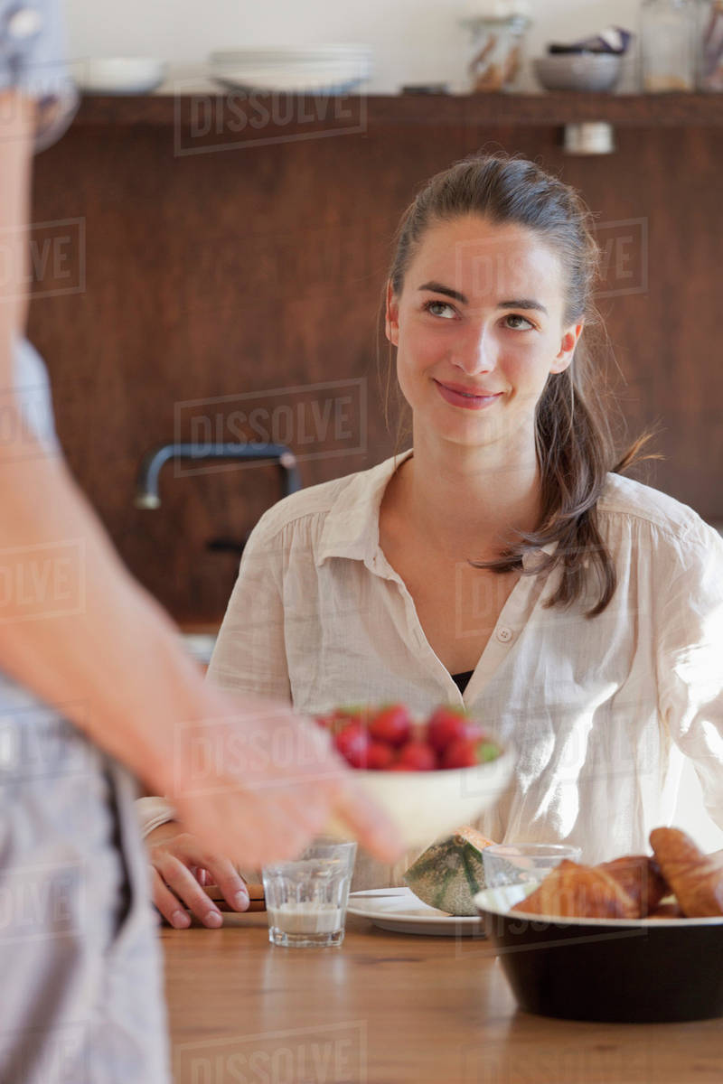 Young woman sitting at dining table with breakfast, smiling - Royalty ...
