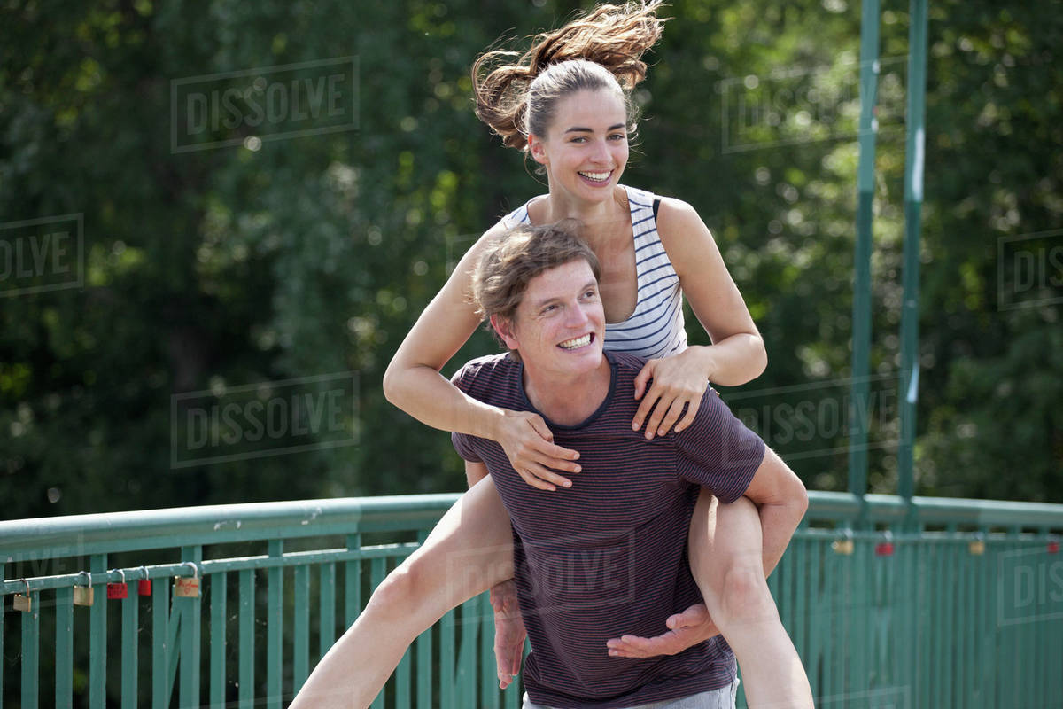 Young man giving woman piggyback ride - Stock Photo - Dissolve