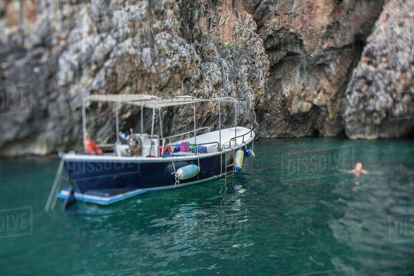 Boat floating on water by rock formation - Stock Photo - Dissolve