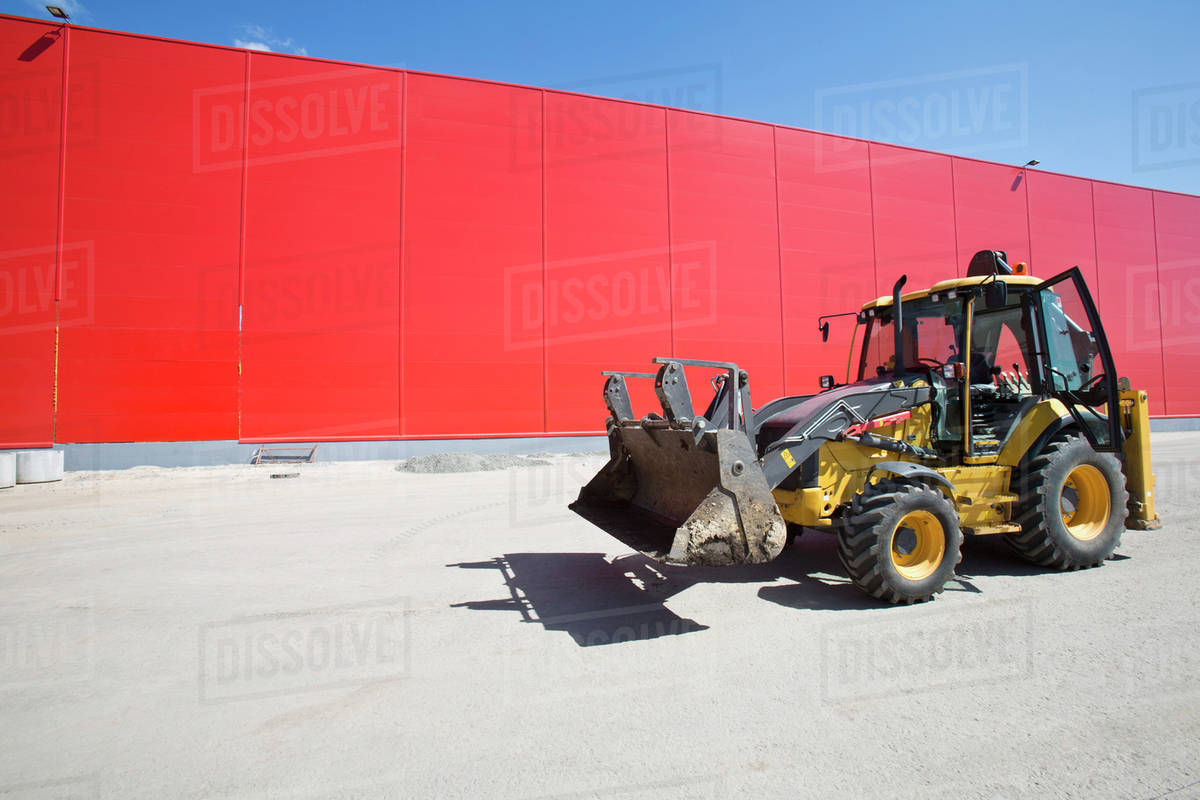 Bulldozer beside red wall - Stock Photo - Dissolve