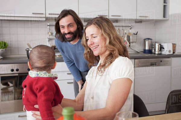Happy parents looking at baby girl in kitchen - Royalty-free Stock ...