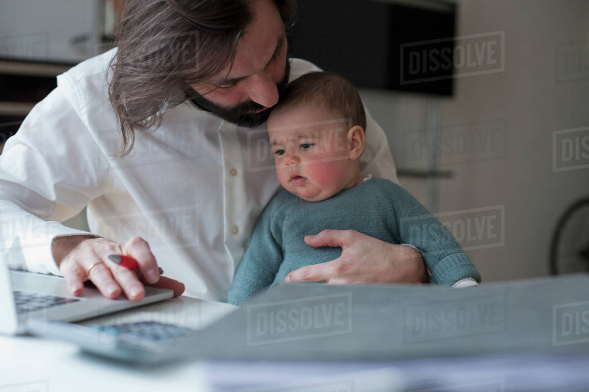 Man looking at baby girl while working at home - Royalty-free Stock ...