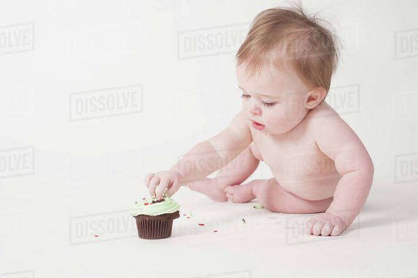 Full length of baby boy eating cupcake against white background - Stock ...