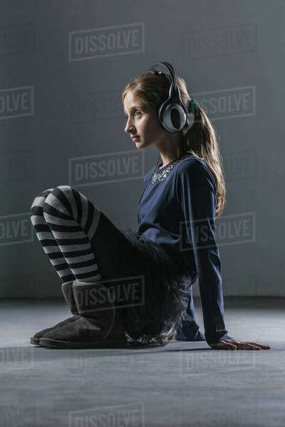 Full length side view of girl crouching while listening music through ...
