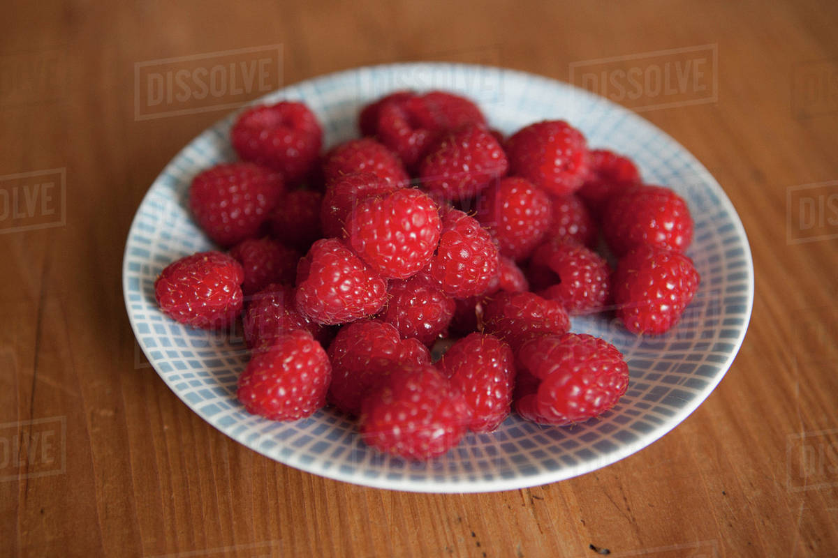 Raspberries in plate on wooden table - Royalty-free Stock Photo | Dissolve