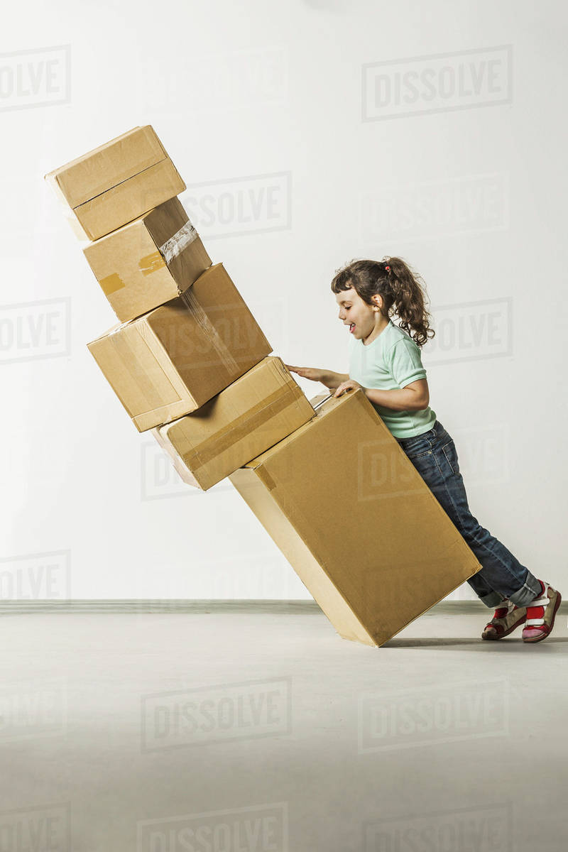 Full length side view of girl dropping boxes in house - Stock Photo ...