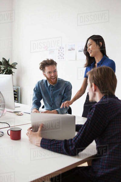 Happy business people communicating at desk in office - Royalty-free ...