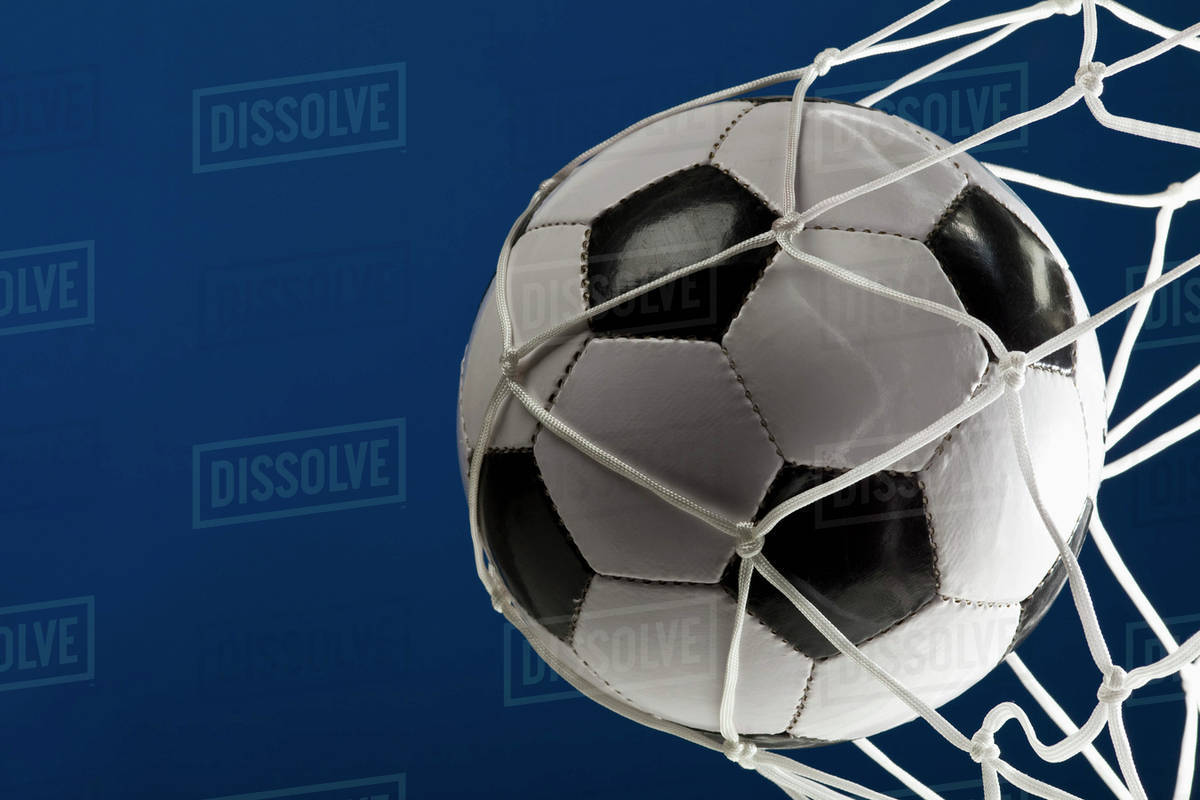 A soccer ball in a net, close-up - Stock Photo - Dissolve