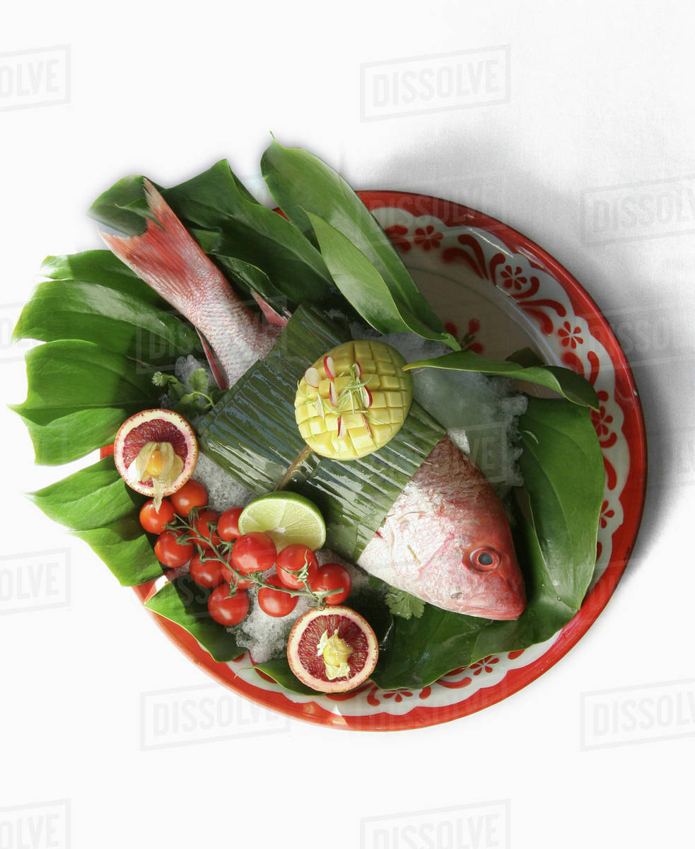 Red snapper wrapped in a banana leaf with garnish - Stock Photo - Dissolve
