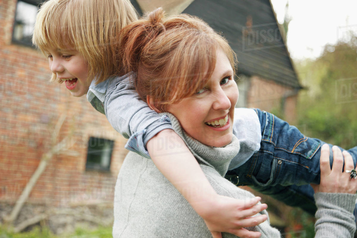 A mother holding her son over her shoulder - Stock Photo - Dissolve