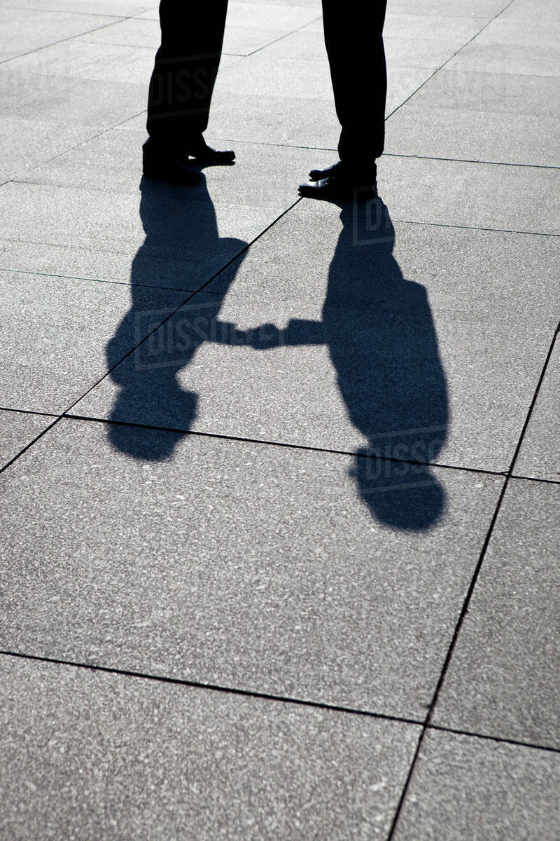 The shadow of two businessmen shaking hands, focus on shadow - Stock ...