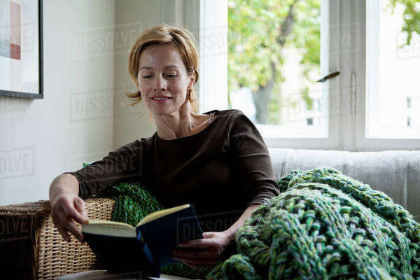 A woman reading a book while reclining on a sofa - Royalty-free Stock ...