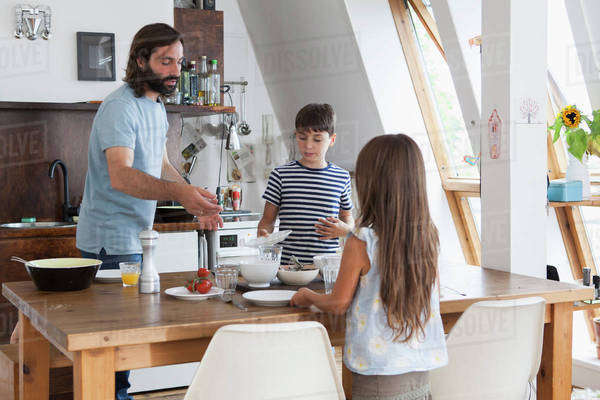 Father and children setting table for lunch in kitchen - Royalty-free ...