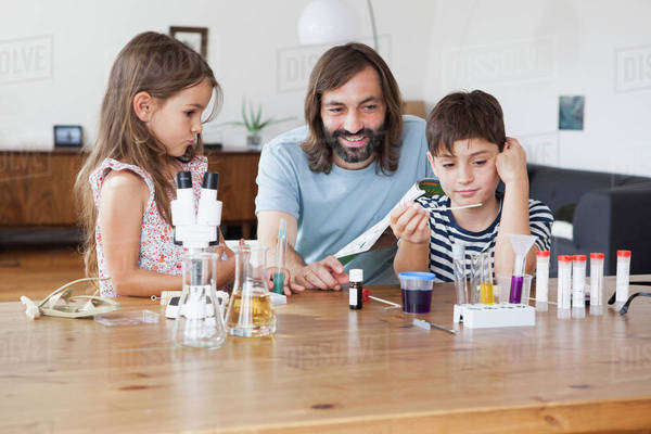 Happy father and children doing school science project at home ...