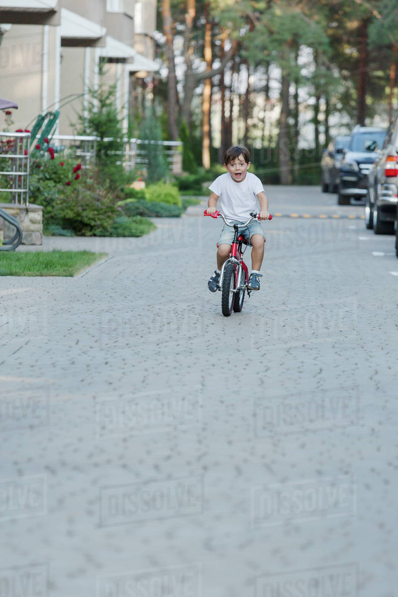 Boy riding bicycle on street - Royalty-free Stock Photo | Dissolve