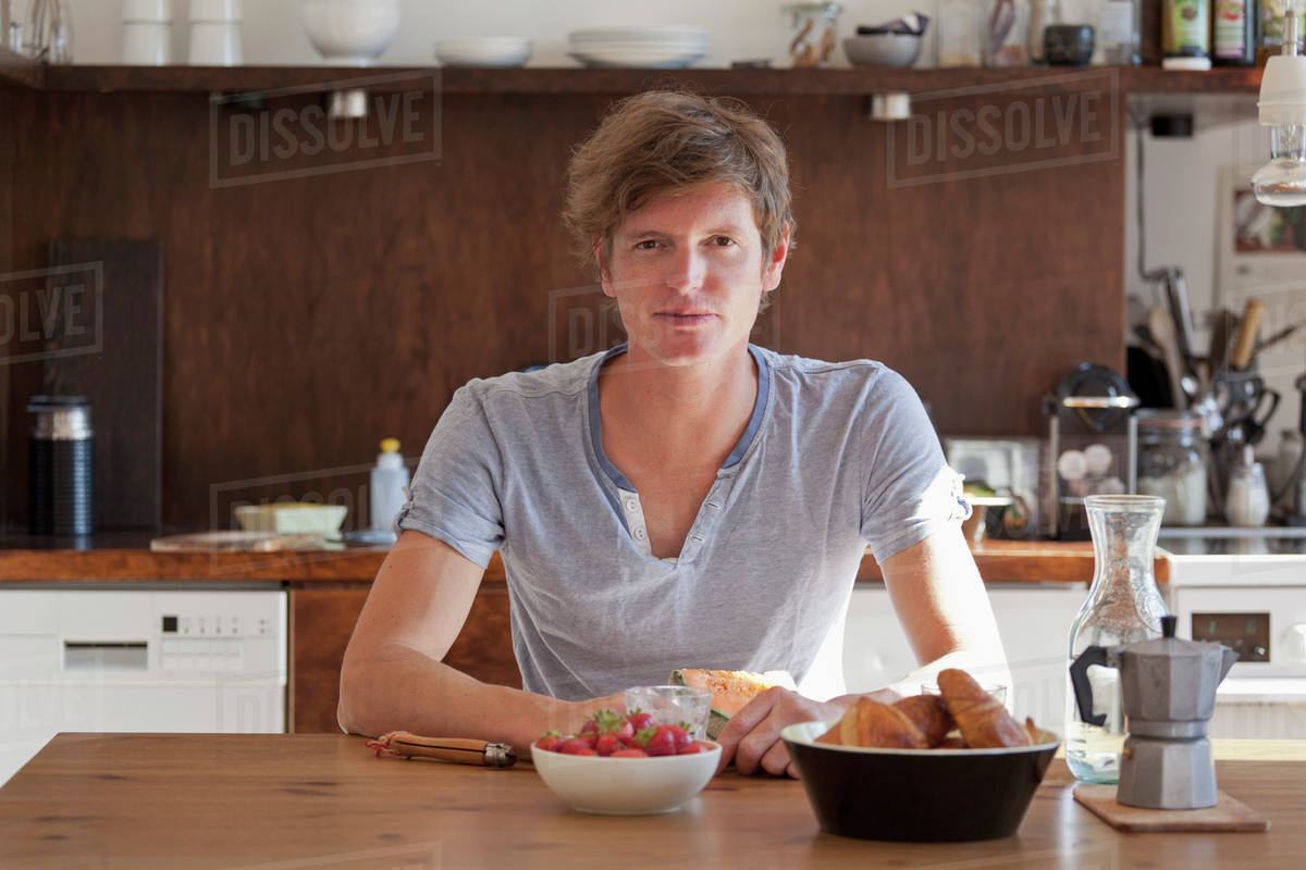 Young man sitting at dining table with breakfast, portrait - Royalty ...