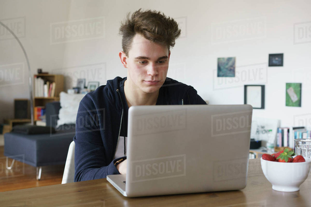 Teenage boy using laptop on table at home - Royalty-free Stock Photo ...