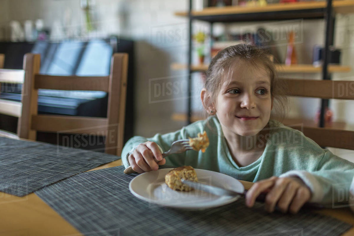 Smiling holding eating food while sitting at table - Stock Photo - Dissolve