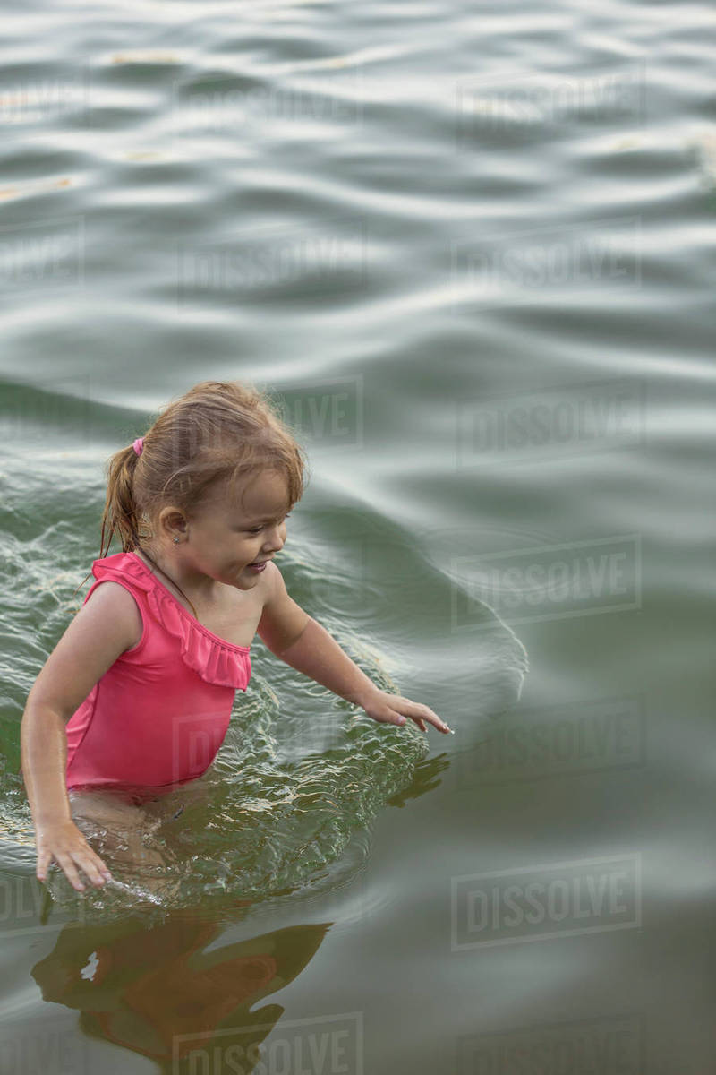 Cheerful girl wearing pink swimsuit standing in lake - Royalty-free ...
