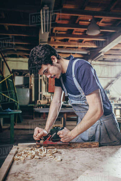 Carpenter planing timber at workshop - Royalty-free Stock Photo | Dissolve