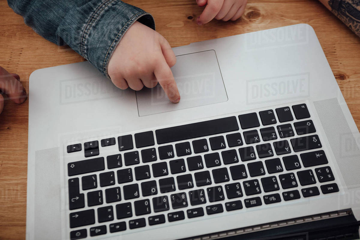 Cropped image of girl scrolling on laptop at wooden table - Royalty ...