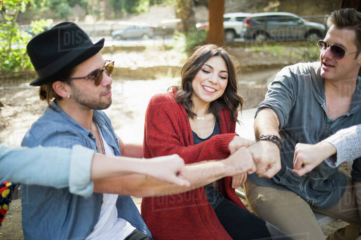Cheerful male and female friends doing fist bumps at park - Royalty ...