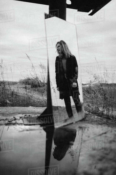 Teenage girl reflecting on glass by field against sky - Royalty-free ...