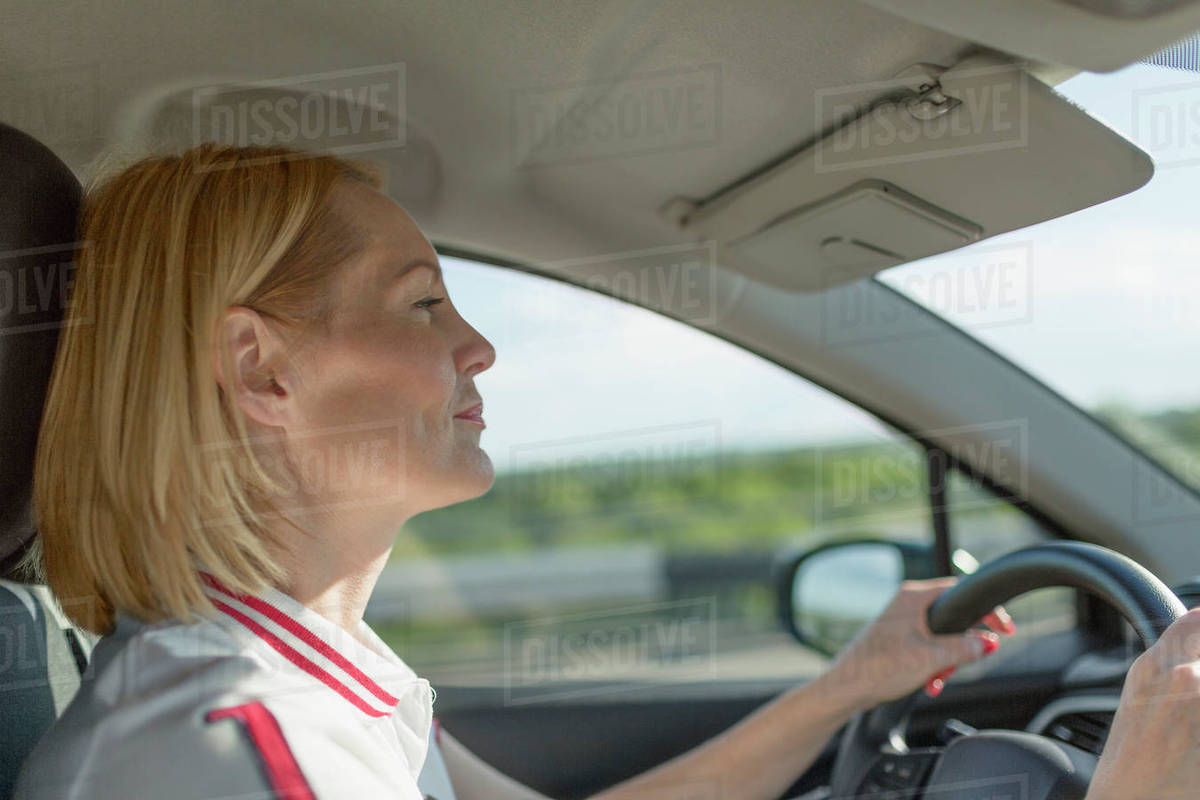Side view of confident mature woman driving car on sunny day - Royalty ...