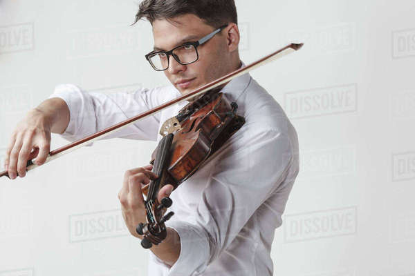 Confident young man playing violin against white background - Royalty ...