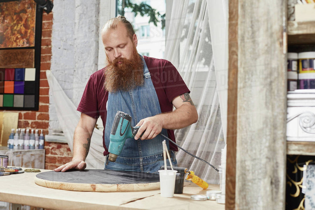 Man drying paint on wood with dryer at workshop - Royalty-free Stock ...