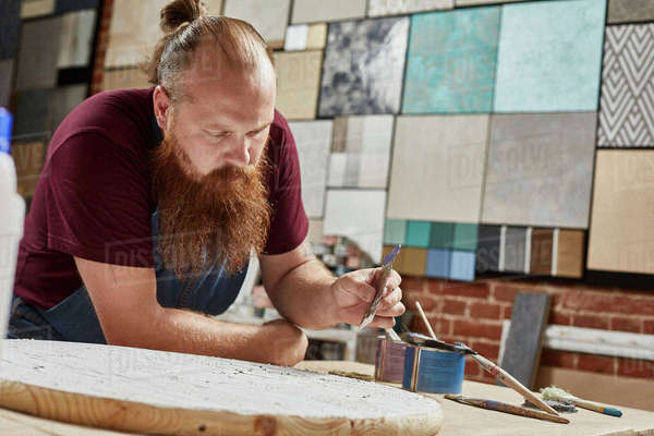 Man holding sand paper while leaning on workbench - Royalty-free Stock ...
