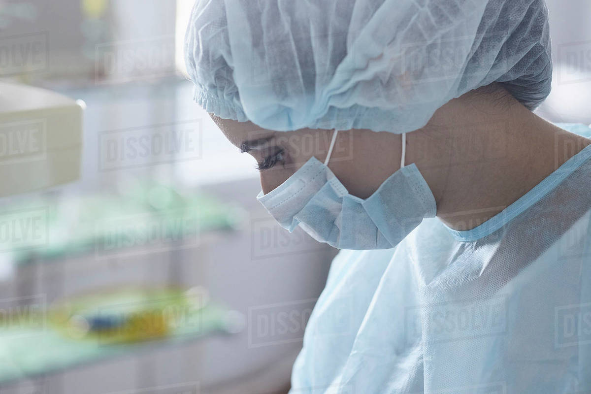 Close-up of surgeon wearing surgical mask and cap working at operating ...