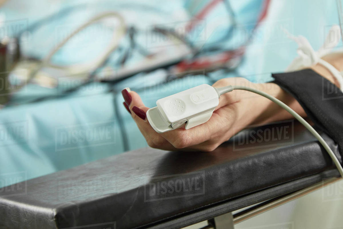 Cropped image of patient wearing pulse oxymeter while lying on bed at ...