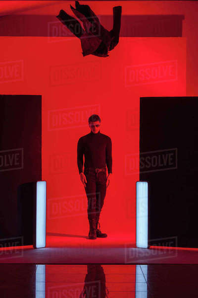 Full length of young man standing below falling jacket amidst ...