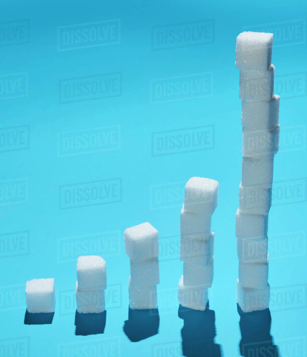 Sugar cubes forming ascending bar graph on blue background - Stock ...