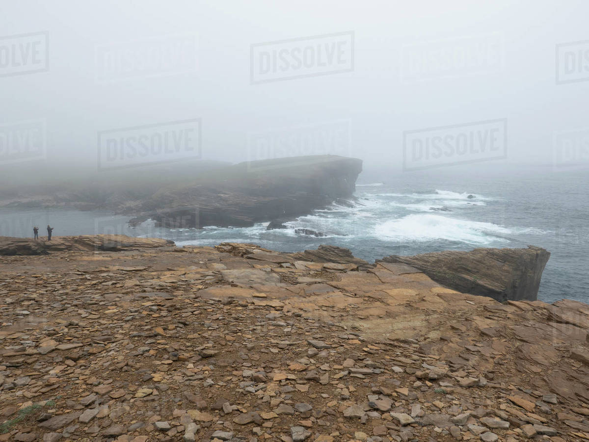 Tourists on rugged cliff enjoying scenic ocean view, Orkney Islands ...