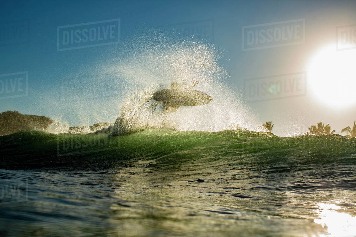 Surfer catching air behind ocean wave at sunrise, Sayulita, Nayarit ...