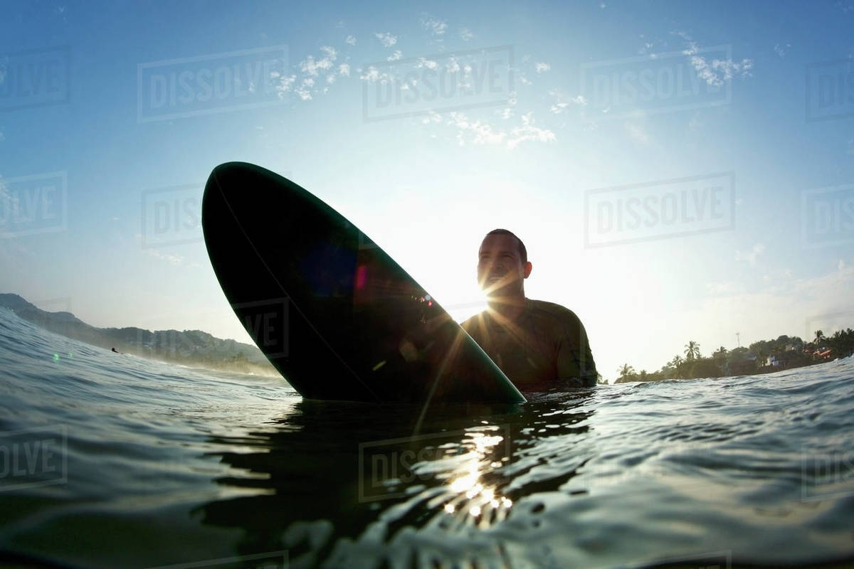 Silhouette male surfer straddling surfboard in sunny ocean - Stock ...