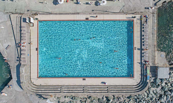Aerial view from above tourists swimming in sunny, blue resort swimming ...
