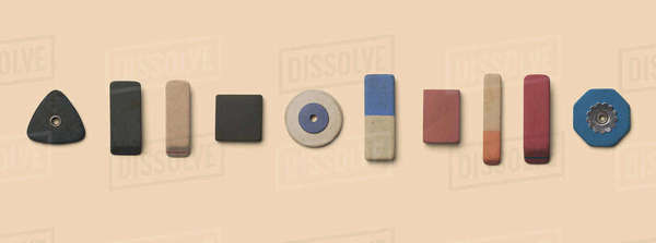 Variety of rubber pieces and erasers in a row on yellow background ...